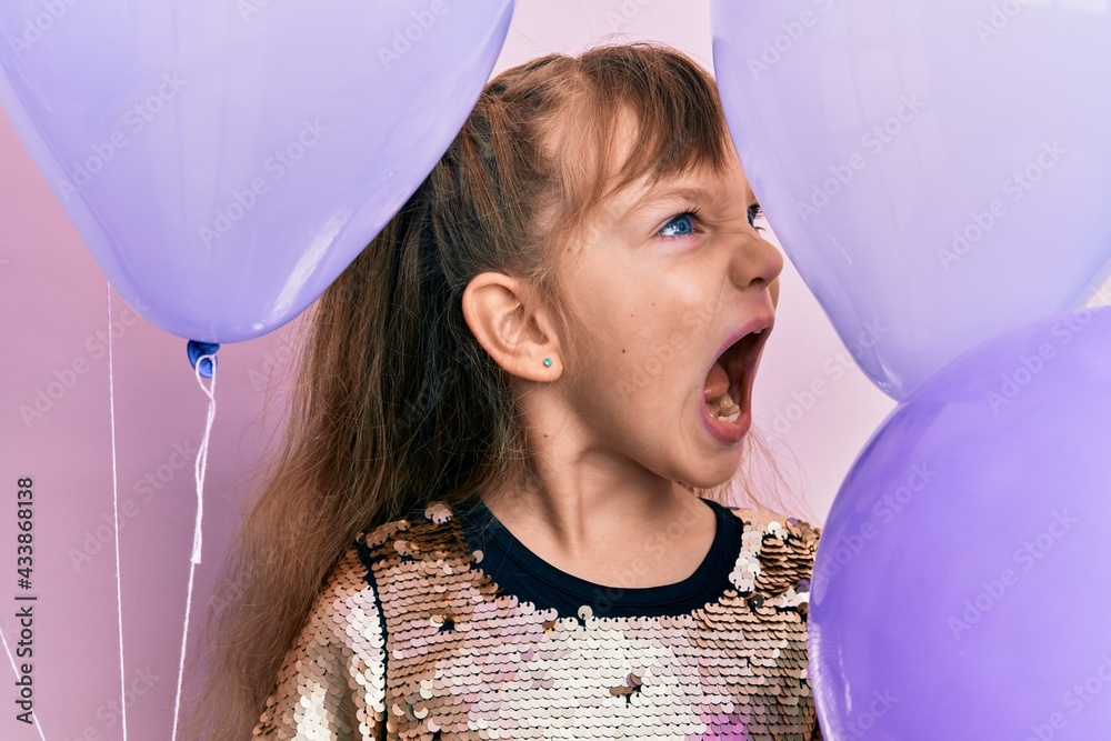 Little caucasian girl kid holding balloons angry and mad screaming ...