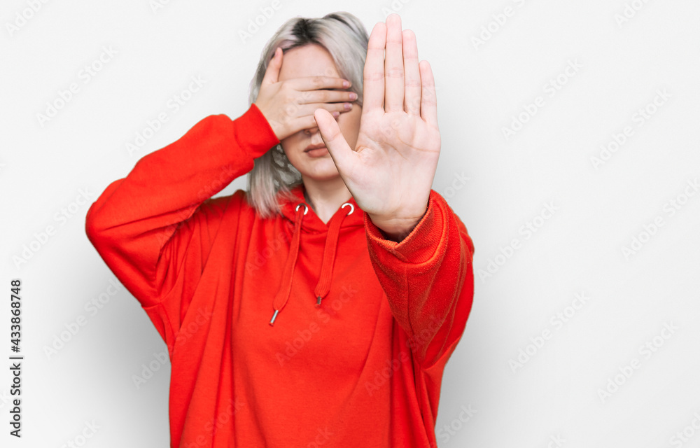 Young blonde girl wearing casual clothes covering eyes with hands and ...