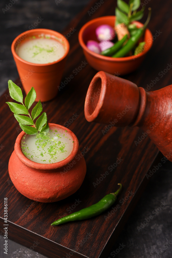 Pouring serving Spiced buttermilk in clay pot , chaas , chaach , moru ...