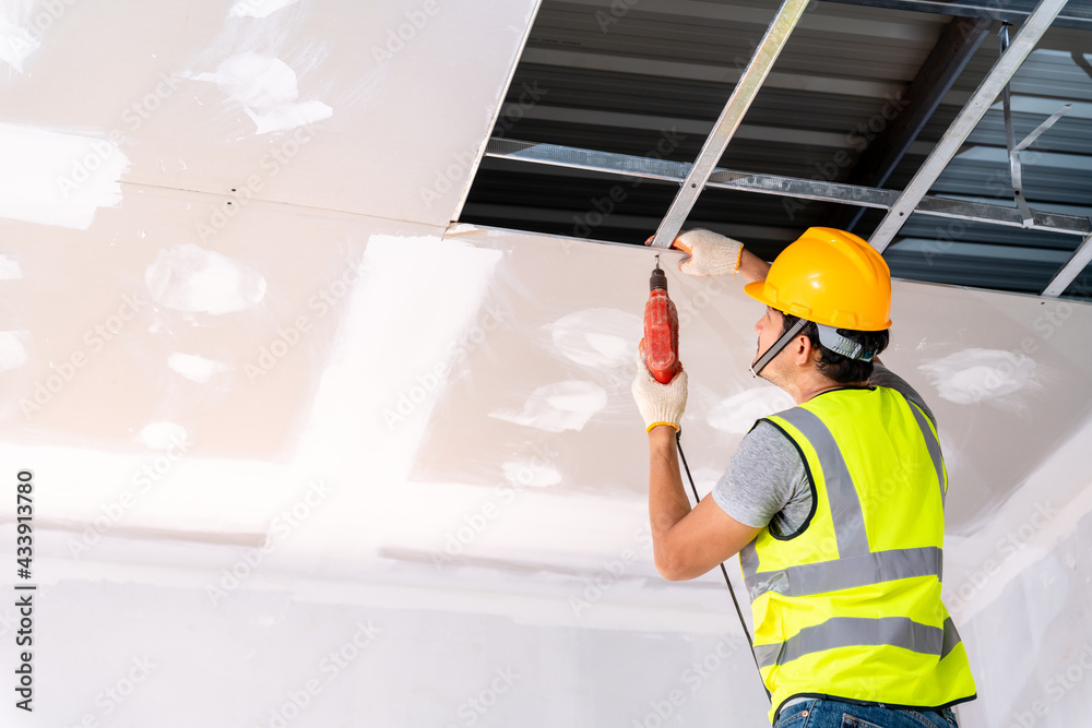 Construction workers using an electric drill are install the ceiling ...
