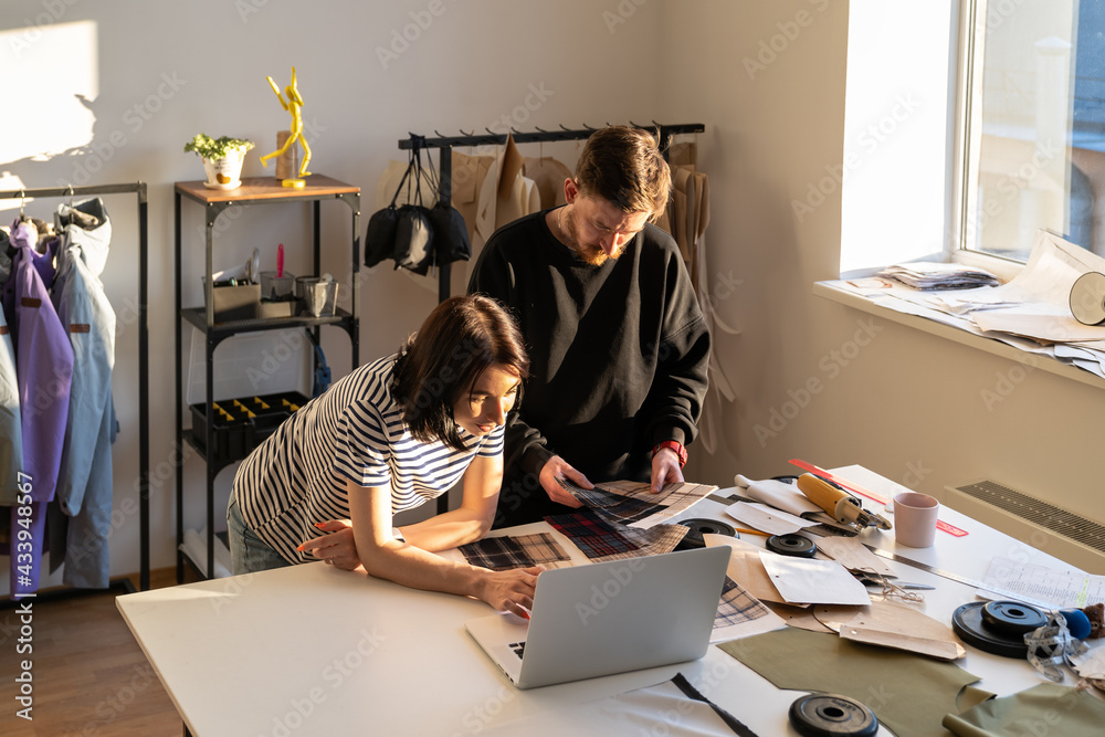 Team of fashion designers working together in studio. Young tailors man ...