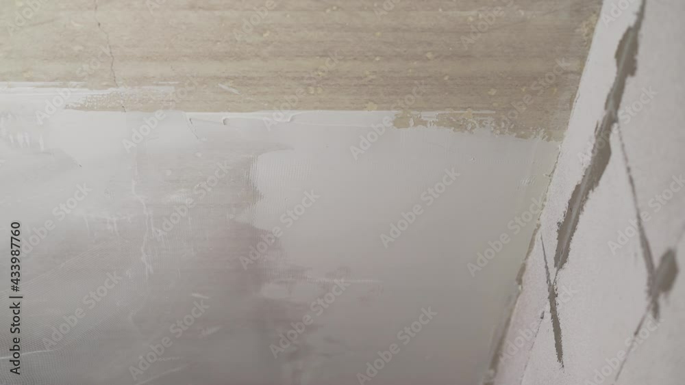 A man puts putty on the ceiling during renovation work. Hand with a ...