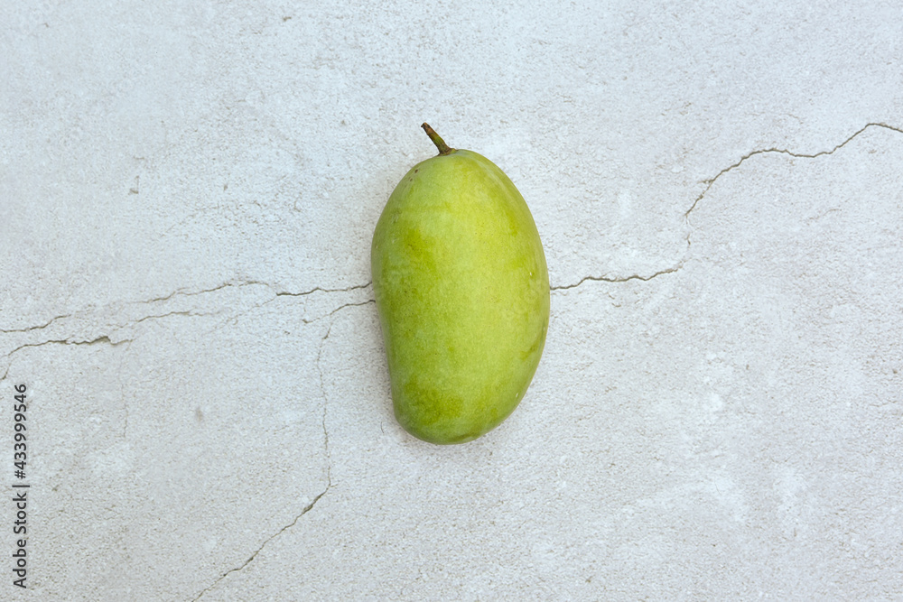 Green mango on grungy cement floor background, a fresh mango organic ...