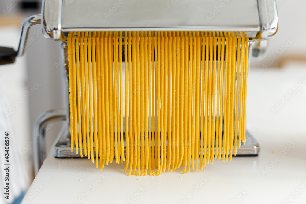 Man in apron making spaghetti with noodle cutter. Close-up pasta ...