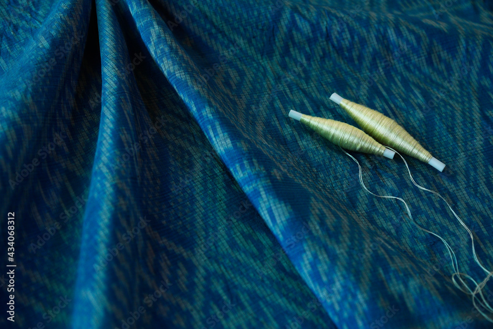 Spool of thread with traditional Thai silk fabric pattern as background ...