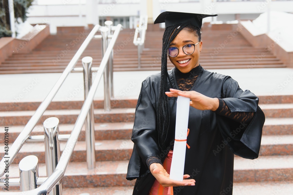 pretty african college student in graduation cap and gown in front of ...