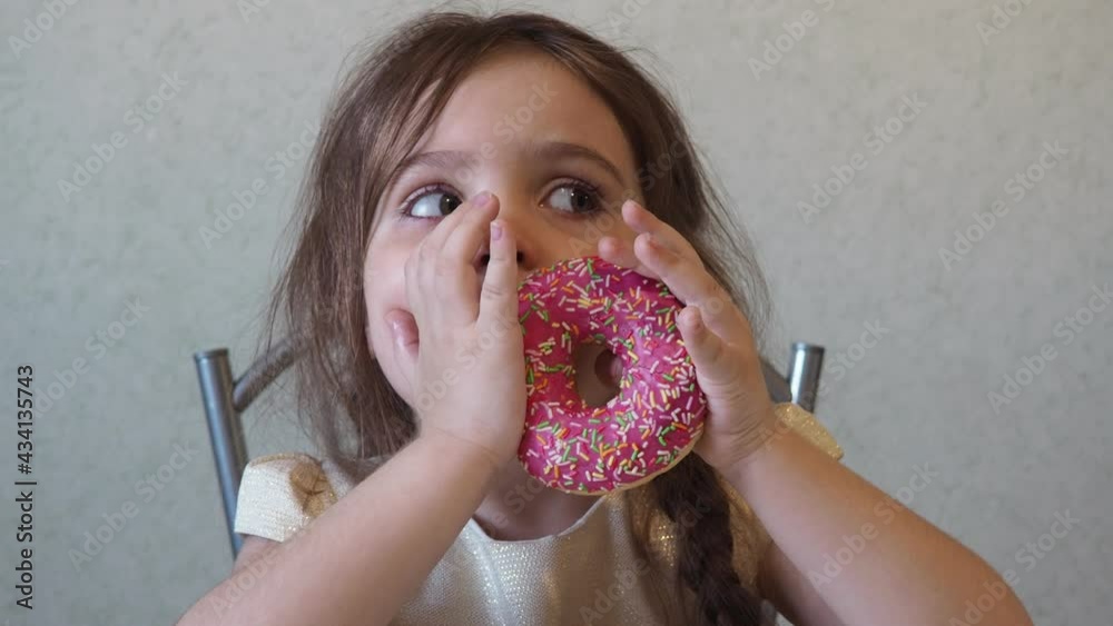 Little happy cute girl is eating donut. child is having fun with donut ...
