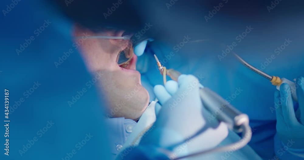 A male patient is laying in a dental chair, having anesthesia while ...