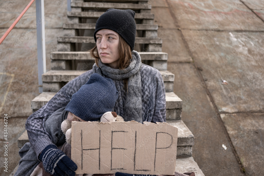 homeless mother with a child with a sign Help on the stairs in an ...