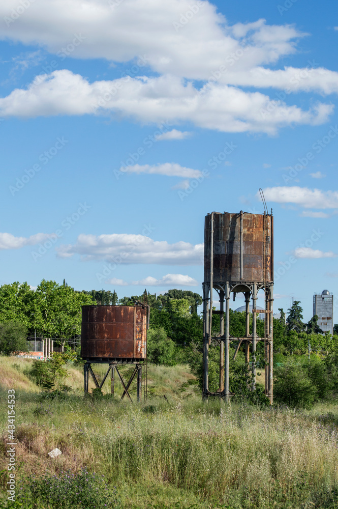two old water tanks in a field where grass grows Stock Photo | Adobe Stock