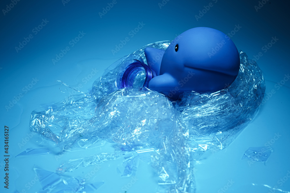 Arrangement of blue toy dolphin wrapped in plastic debris representing ...