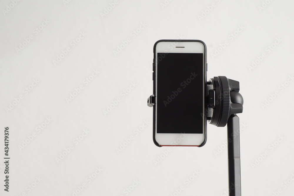 Smartphone mounted on a modern tripod in a vertical position. Space for ...