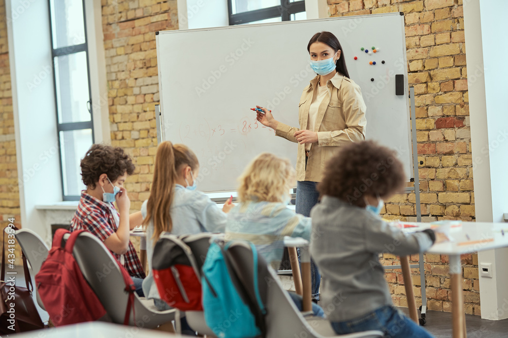 Group of elementary school kids and female teacher wearing protective ...