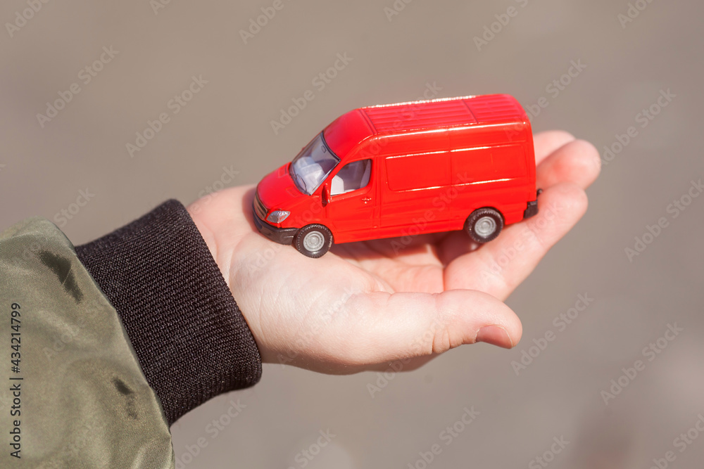 Toy car on a child's hand. Cargo delivery van. Red toy truck. A child ...