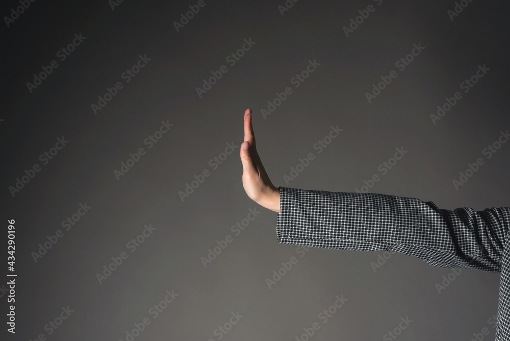 Women hand is showing a stop gesture close up on the gray background ...