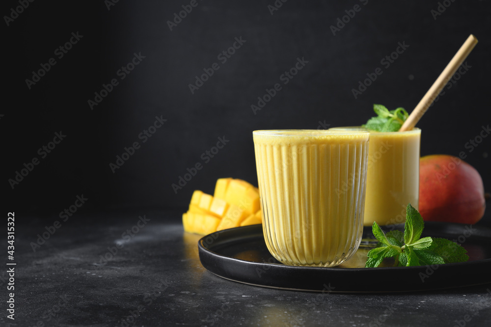 Two mango lassi in glasses on black background with copy space. Indian ...