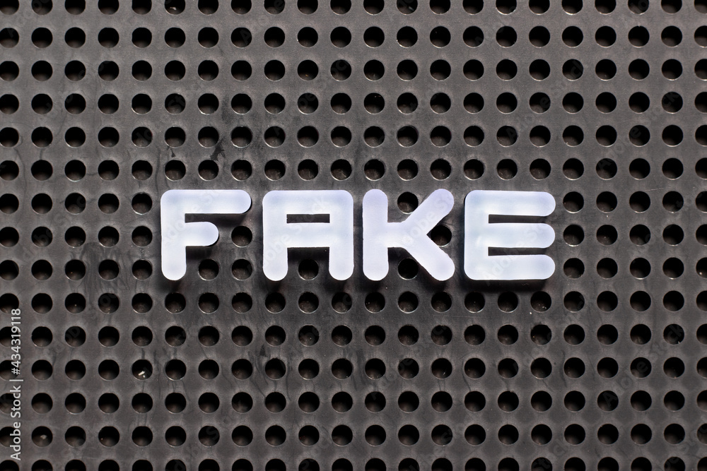 White color letter in word fake on black pegboard background Stock ...