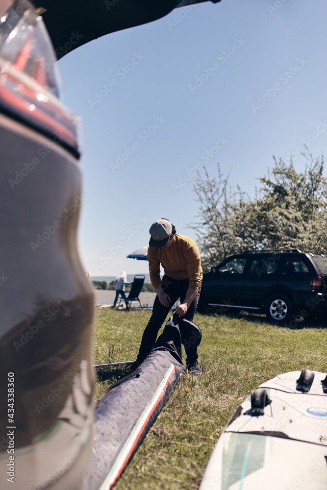 Windsurfer and camper packing and unpacking from a car's roof rack in ...
