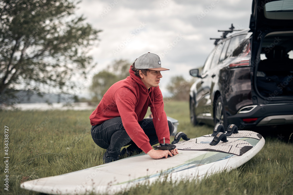 Windsurfer and camper packing and unpacking from a car's roof rack in ...