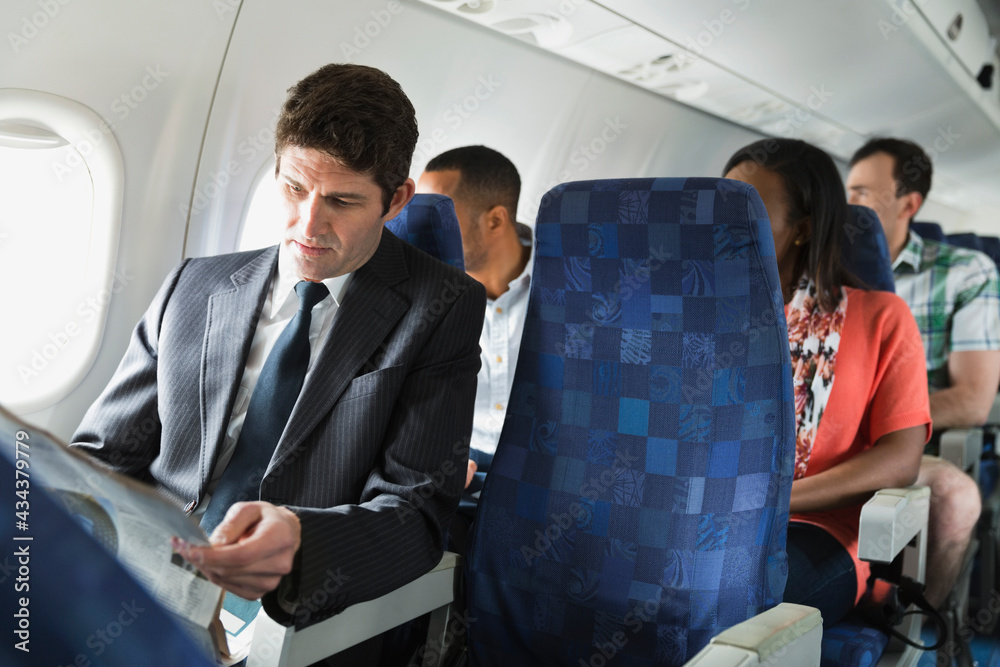 Businessman reading newspaper in airplane Stock Photo | Adobe Stock