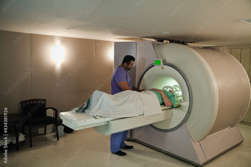 Male radiologist doing CT-Scan on female patient in examination room ...