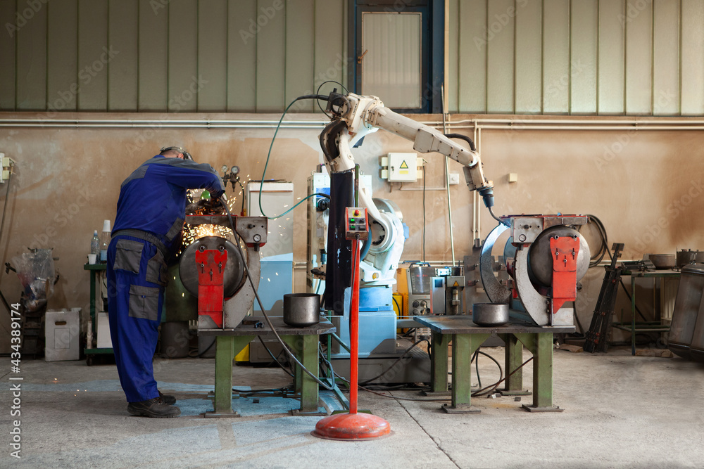 Man and robotic machine work together inside industrial building. The ...