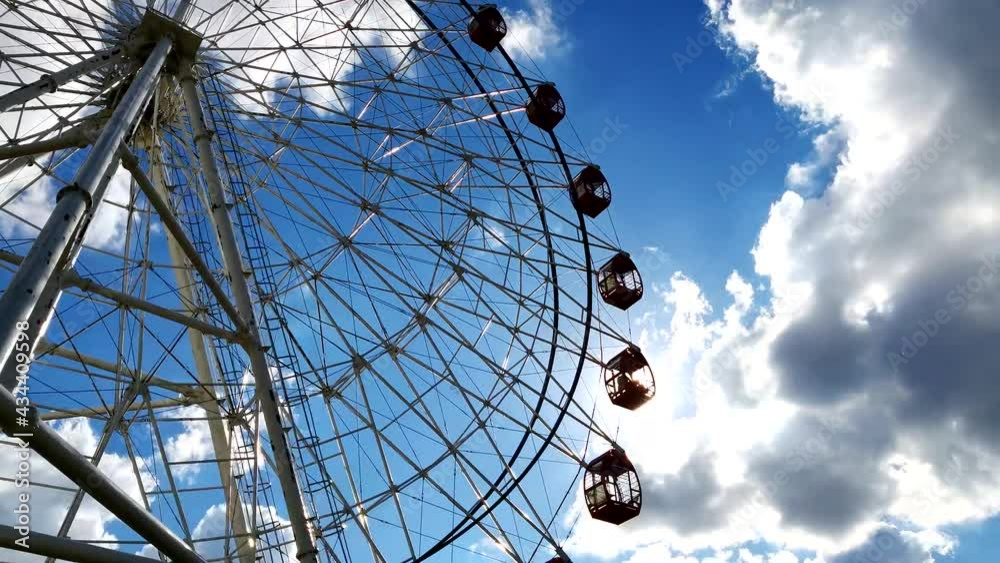 Time lapse of a ferris wheel with shining sun and moving clouds in the ...