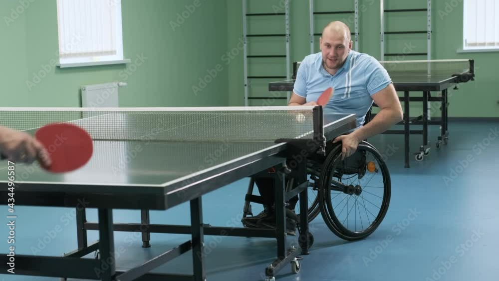 A man in a wheelchair plays ping pong. People with disabilities play ...