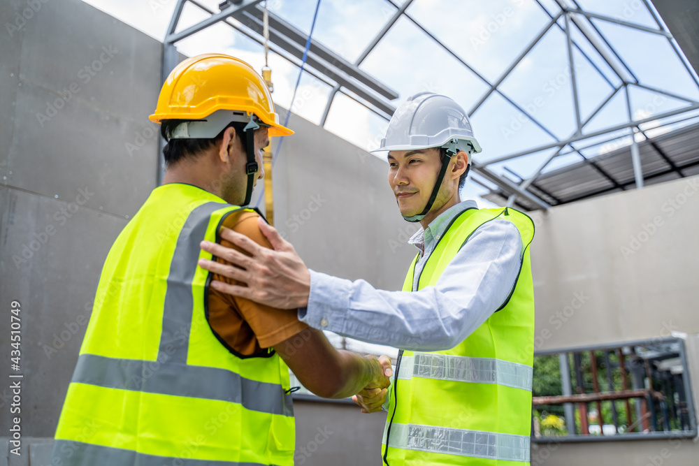 Asian male engineer and worker making handshake on construction site ...