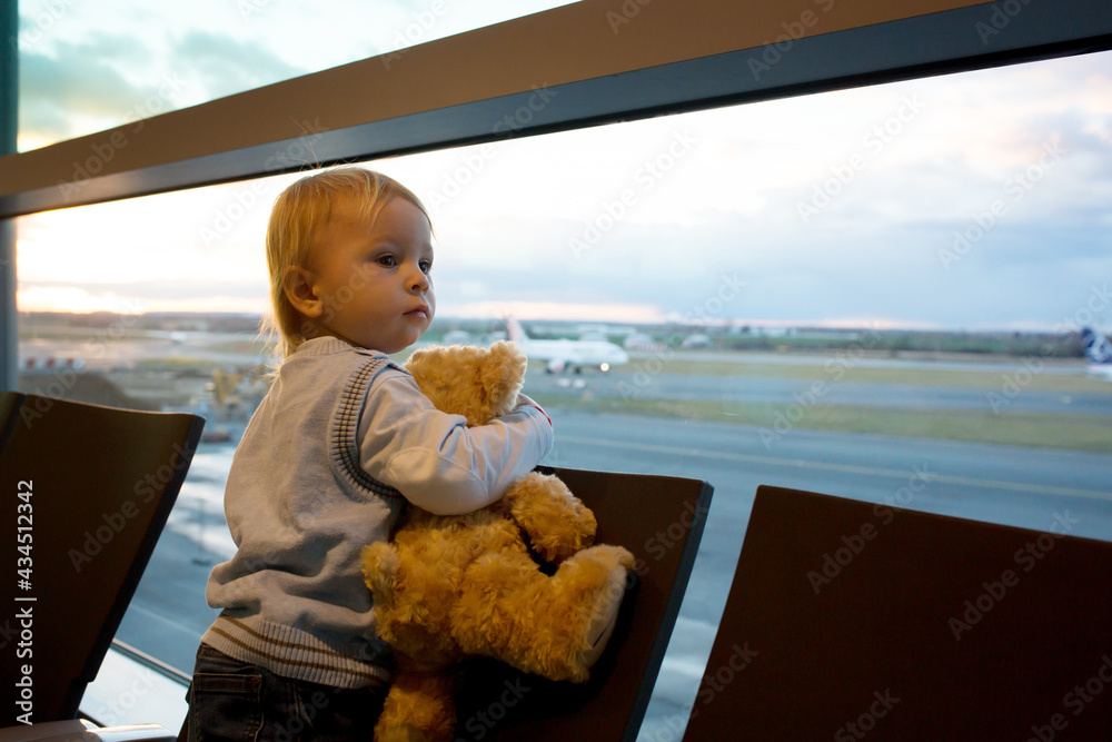 Child, watching from the window of the airport the planes, taking off ...