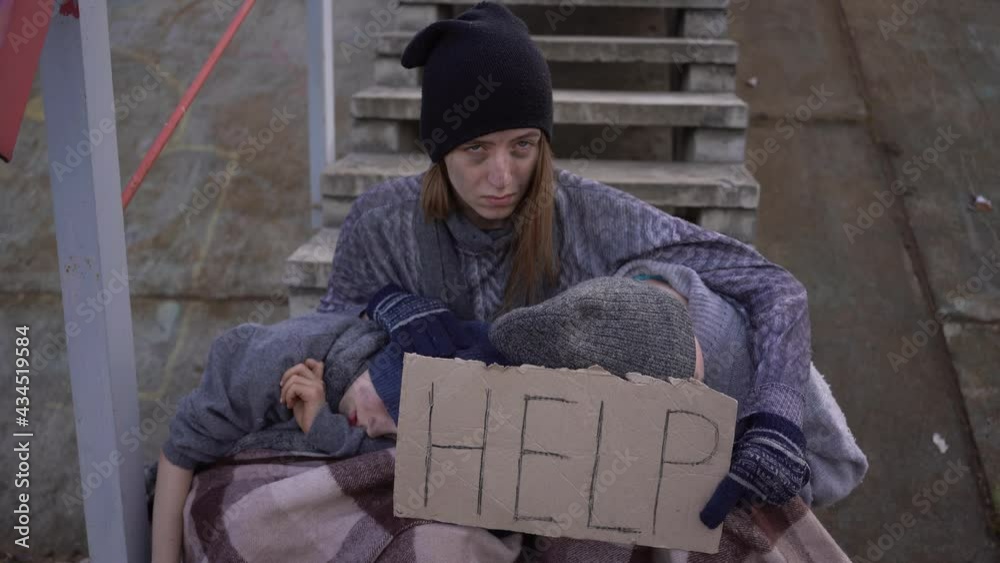 homeless mother with children with a sign Help on the stairs in an ...
