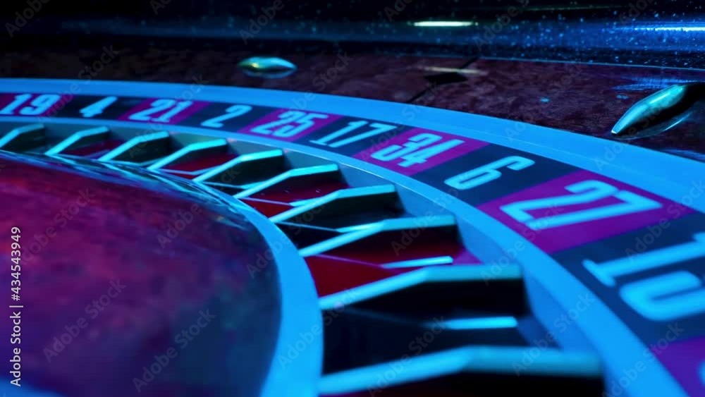 Rotating roulette wheel close up in the rays of blinking neon lights ...