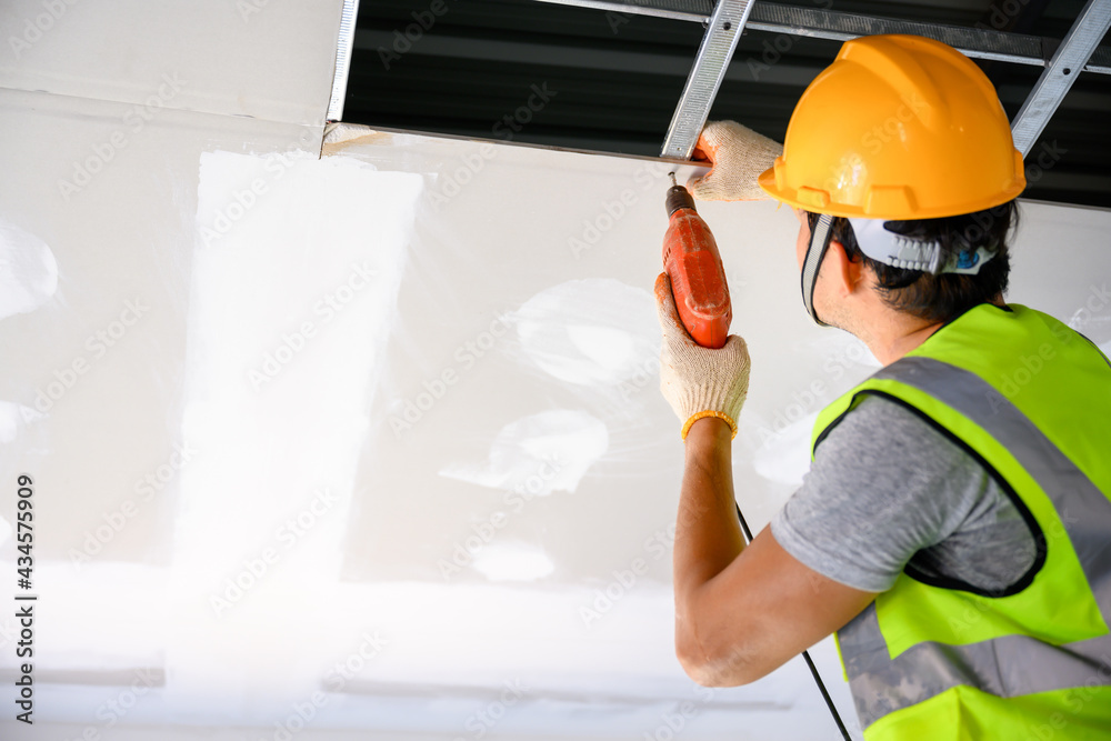 Young male construction workers wearing uniforms Installing gypsum ...