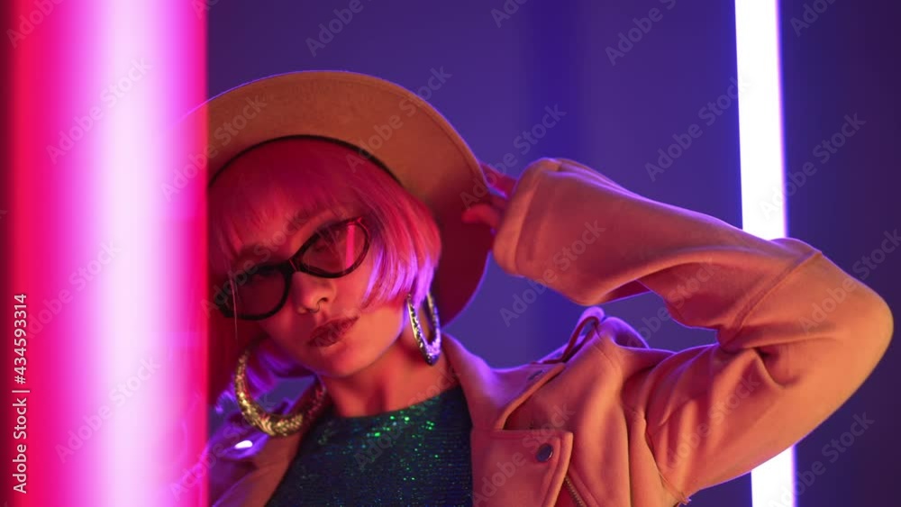 Eccentric woman with pink hair posing near led-colorful neon lamps ...