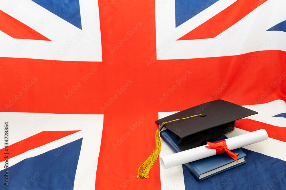 Graduation diploma and academic graduate hat on the UK flag background ...