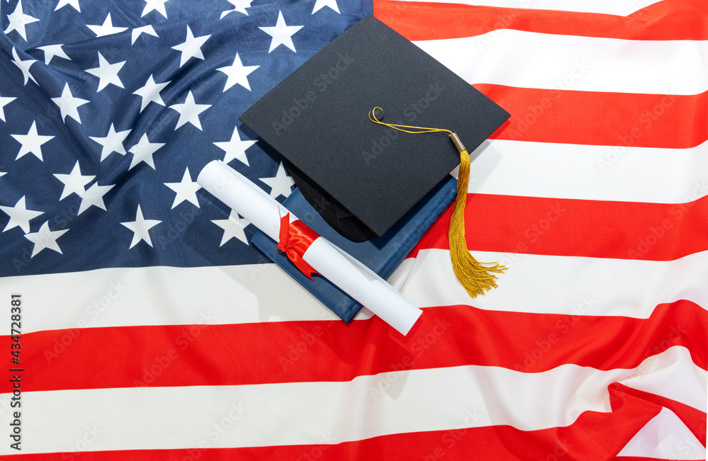 Top view graduation diploma and academic graduate hat on the USA flag ...