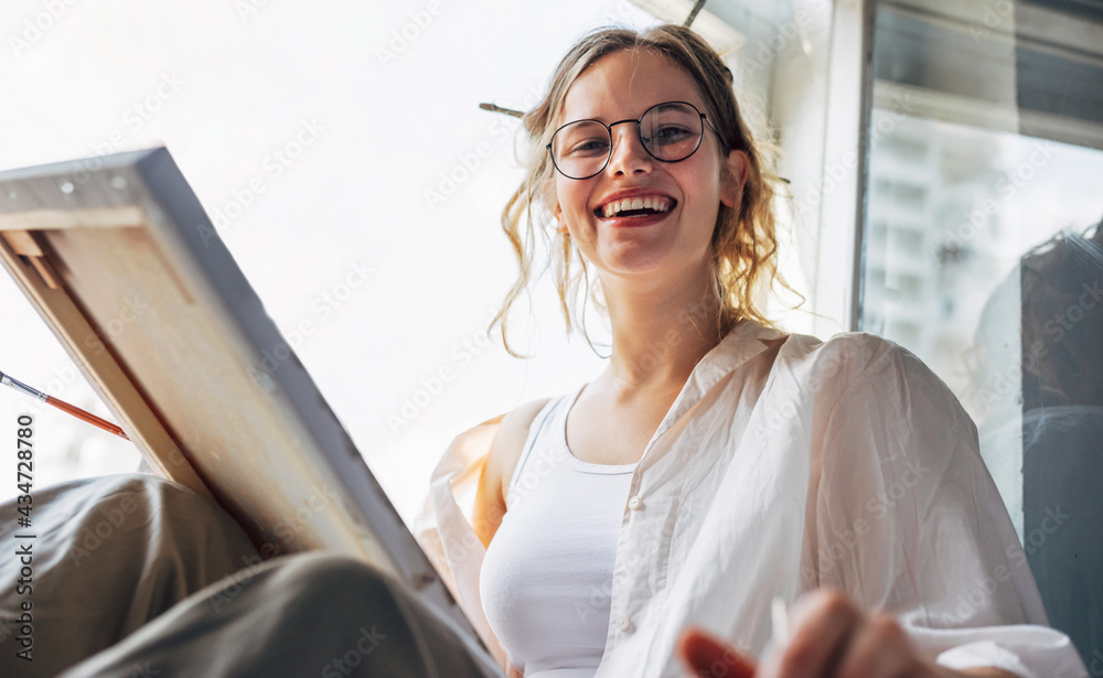 Cheerful female artist painting on canvas in her art studio sitting ...