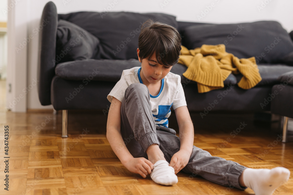 boy trying to puts on socks. he is sitting on floor at home Stock Photo ...