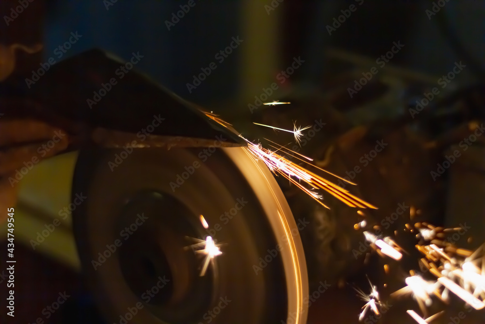 Sharpen the axe tool on the rotating grinding wheel, sparks fly from ...