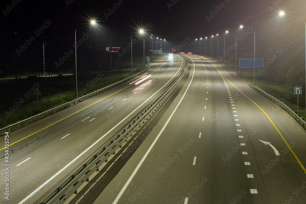 High-speed suburban highway in the light of streetlights. There are ...