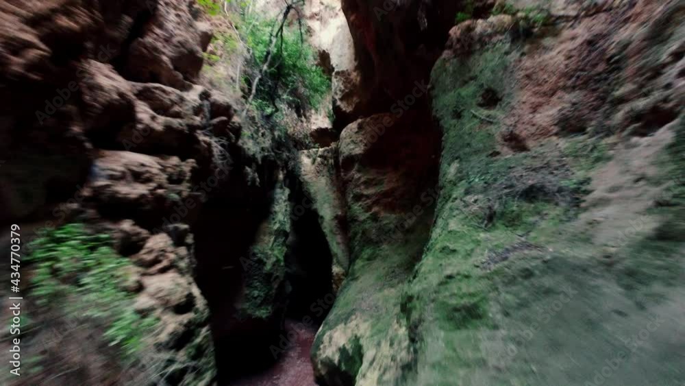 Cave exploration, exploring a cavern. Young woman explorer walks through a narrow path in caves ...