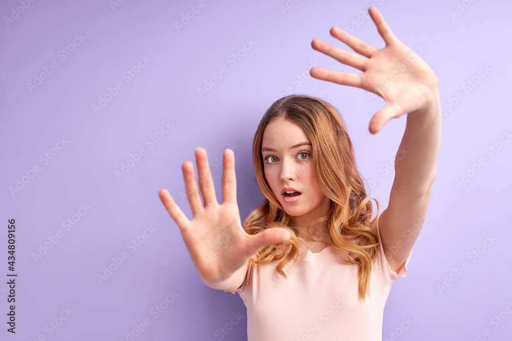Young girl over isolated purple background scared with arms up like ...