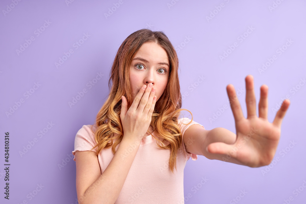 Young girl over isolated purple background scared with arms up like ...