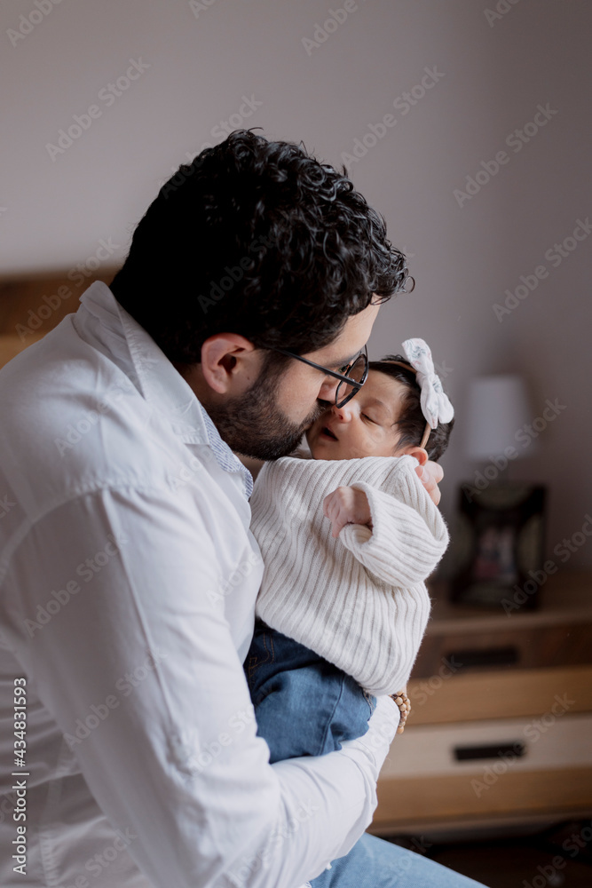 Young Hispanic father kissing his newborn baby at home - New father ...