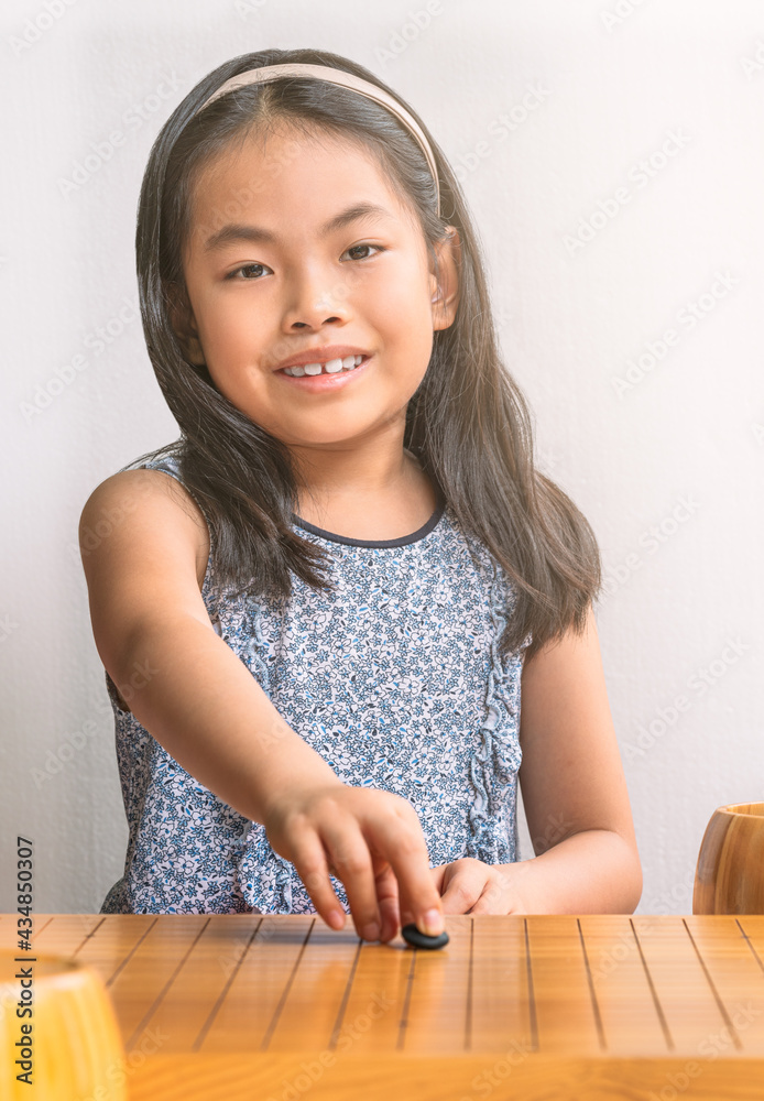 Portrait Asian child girl is playing Go with the first move of black ...