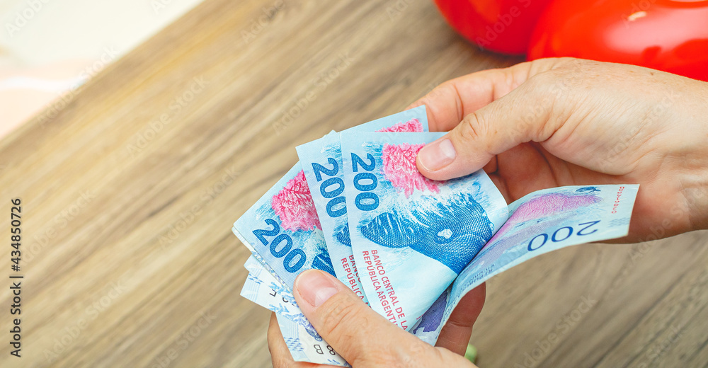 Uma pessoa contando cédulas do dinheiro da Argentina, que é o Peso ...