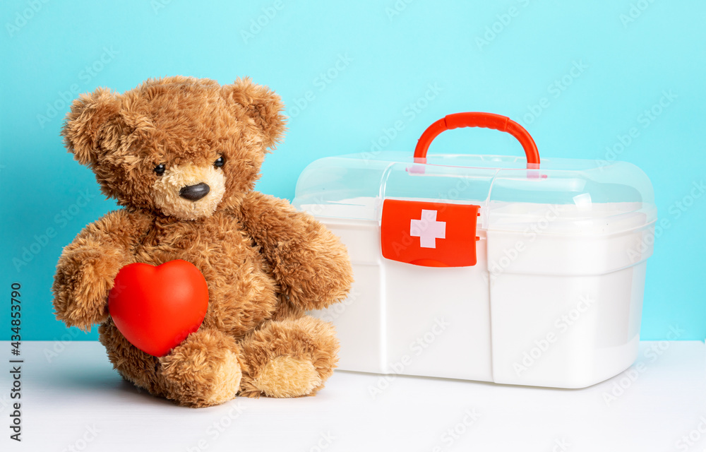 Teddy bear with heart and first aid kit on green background Stock-Foto ...