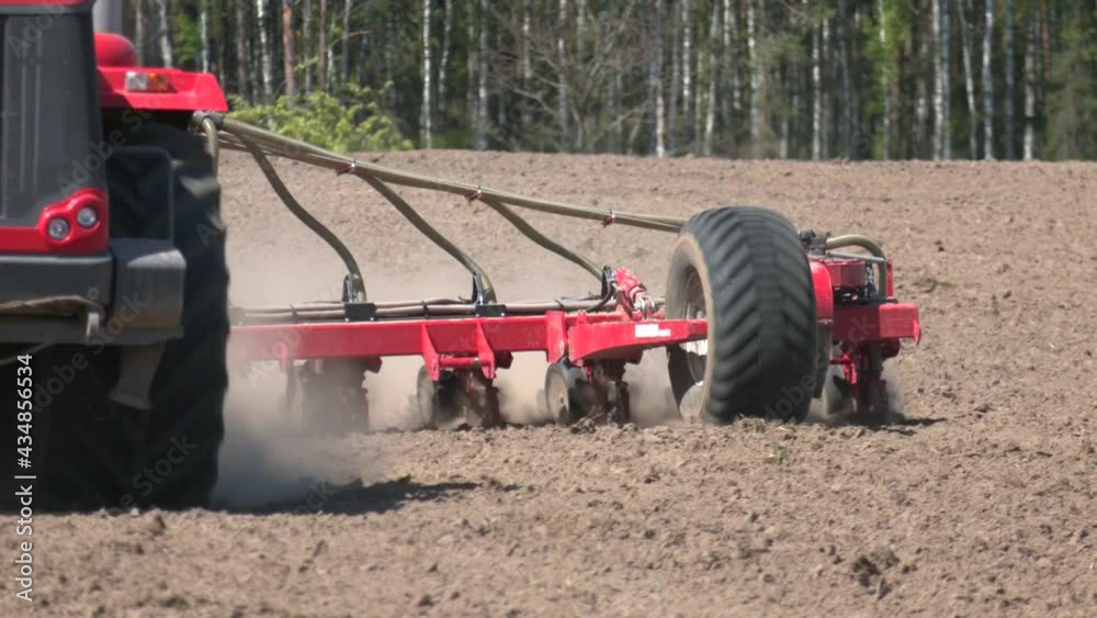 Farmer in tractor sowing crops at field with seed scattering ...
