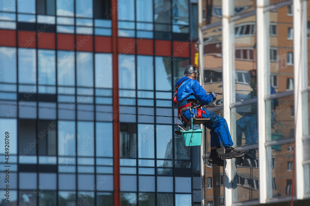 Professional climber rope access worker cleaning the windows on the ...