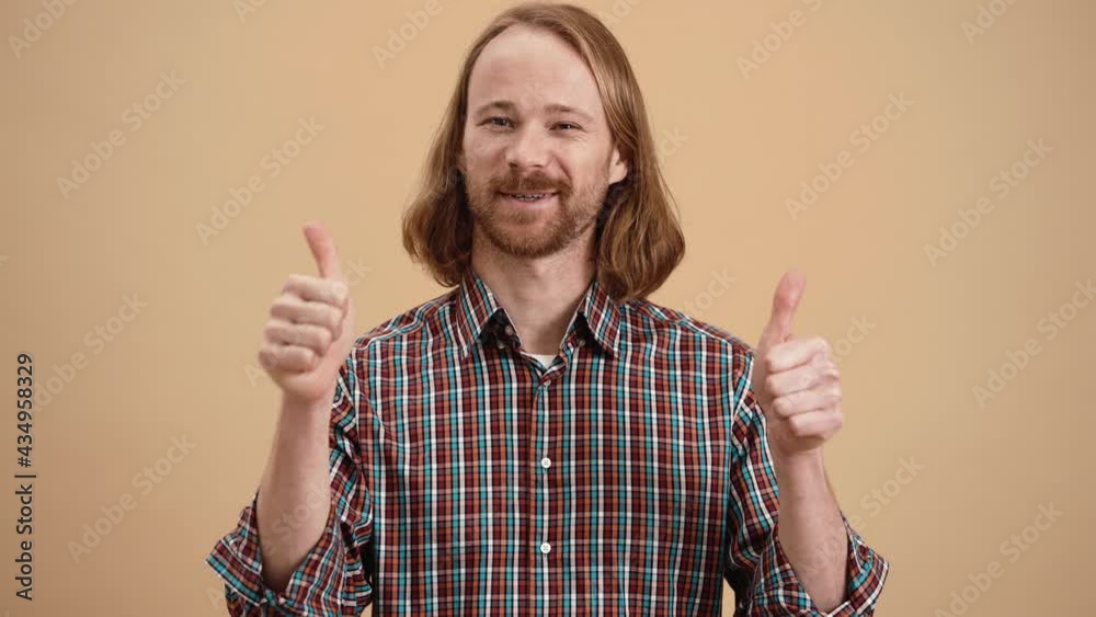A smiling man with long hair in a plaid shirt clapping hands and ...